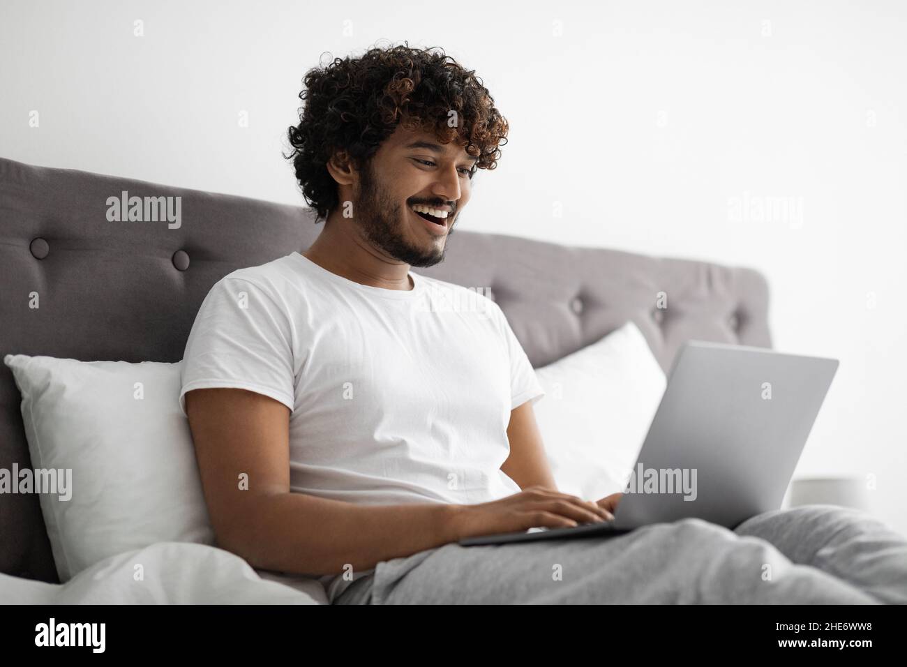 Young indian man typing on laptop, working in bed Stock Photo - Alamy