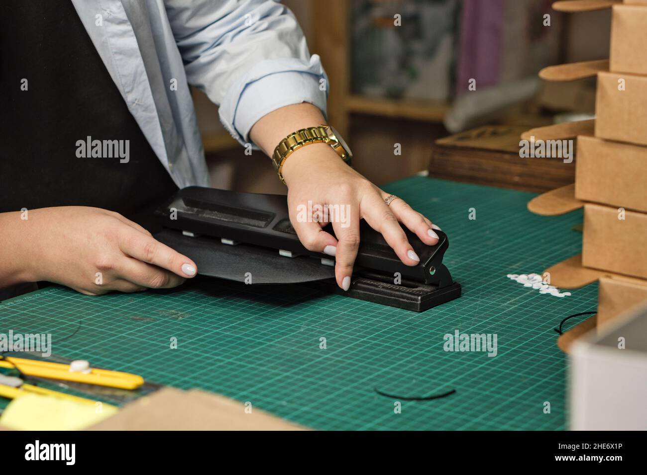 Female hands use hole punch to create perforations in removable paper ...