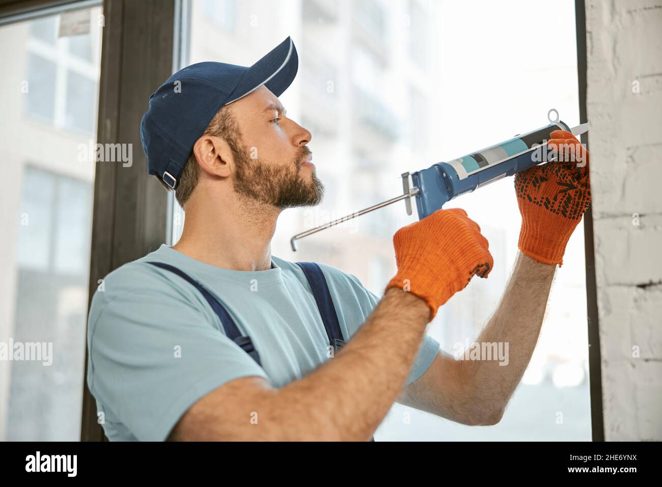 Repairman fixing window with silicone adhesive gun Stock Photo - Alamy