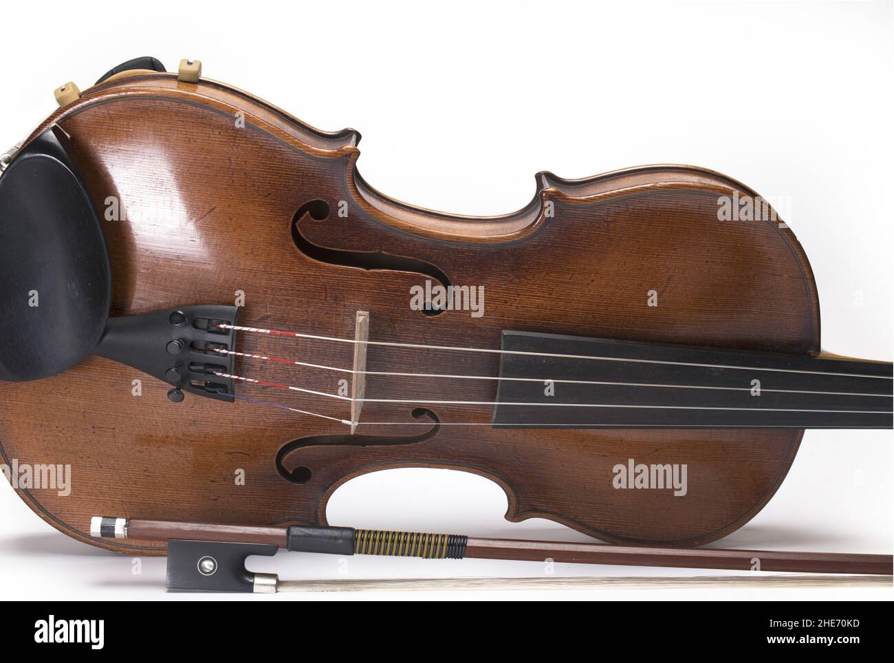 Close up of bow in front of sound body and strings of old violin with ...