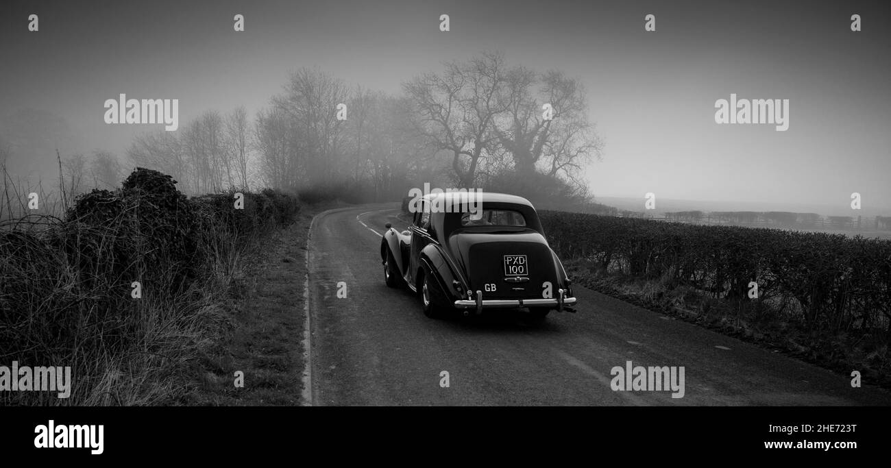 A vintage Rolls Royce from 1955 glides through the foggy landscape at ...