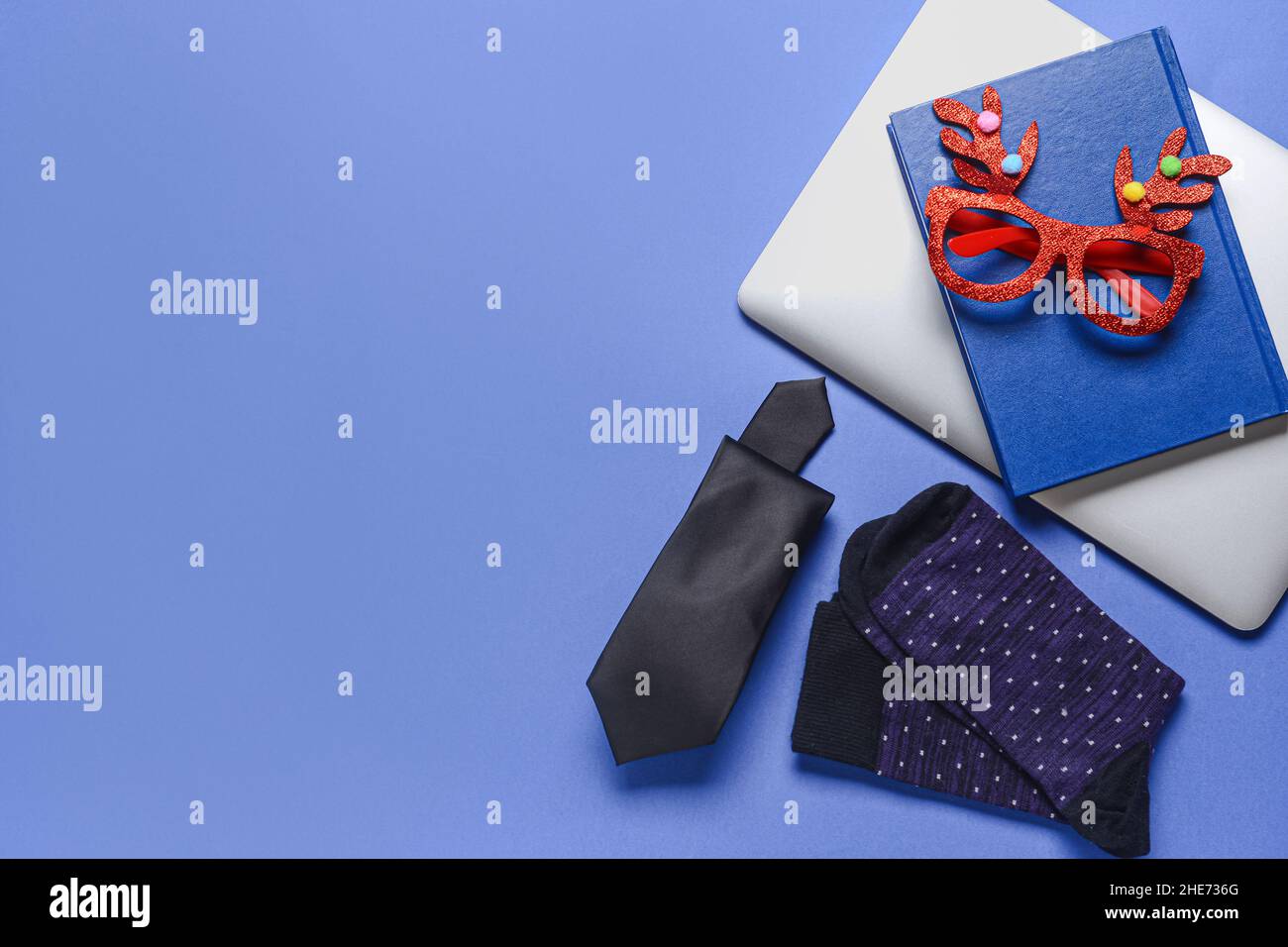 Laptop with party decor, necktie and socks on color background Stock ...