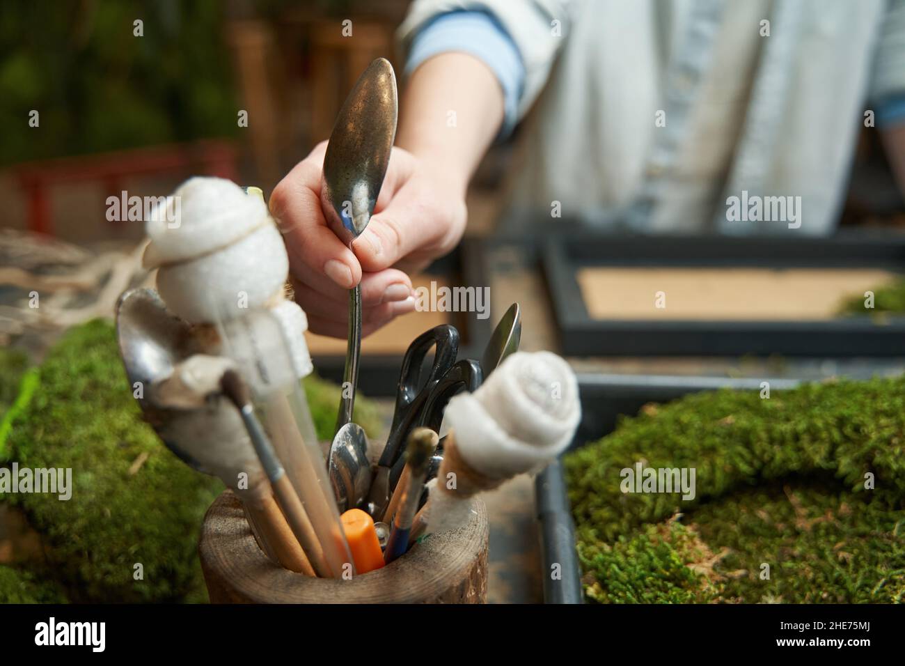 Woman taking spoon from wooden can with instruments Stock Photo - Alamy