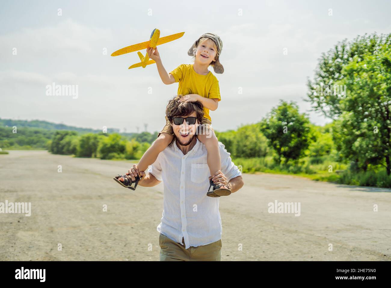 Happy father and son playing with toy airplane against old runway ...