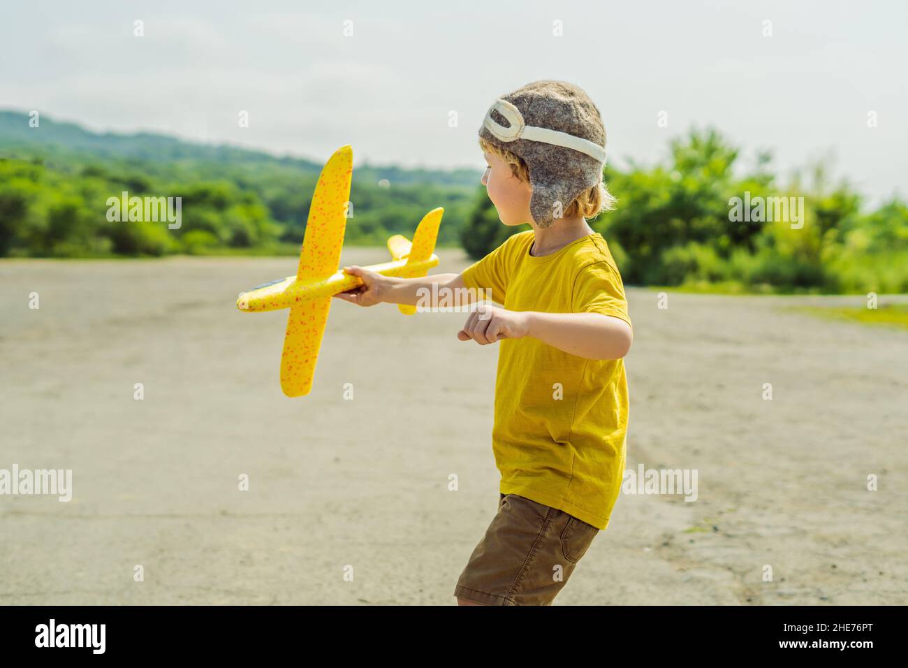 Happy kid playing with toy airplane against old runway background ...