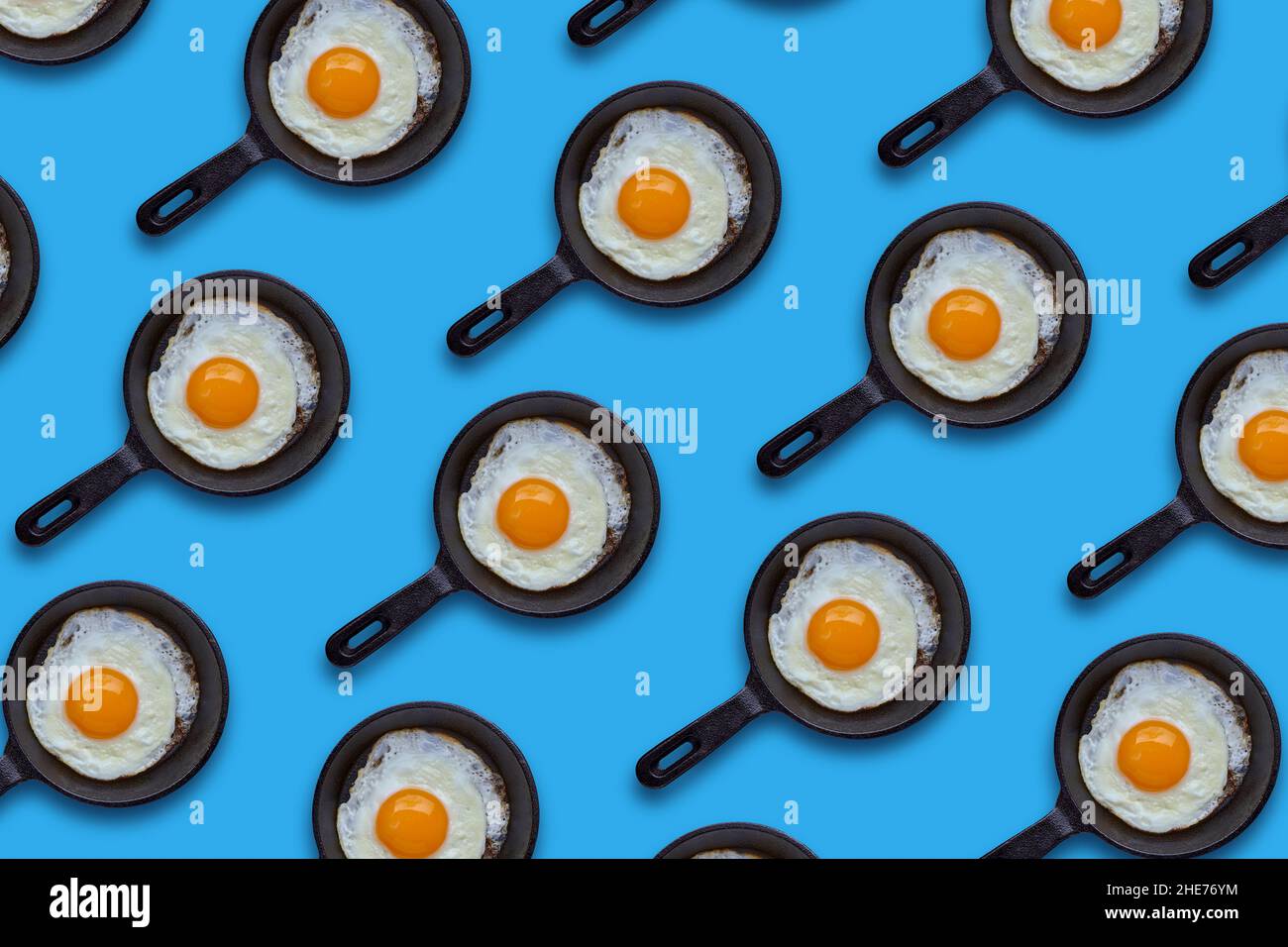 Cast iron frying pan with a fried egg on a blue background. Seamless ...
