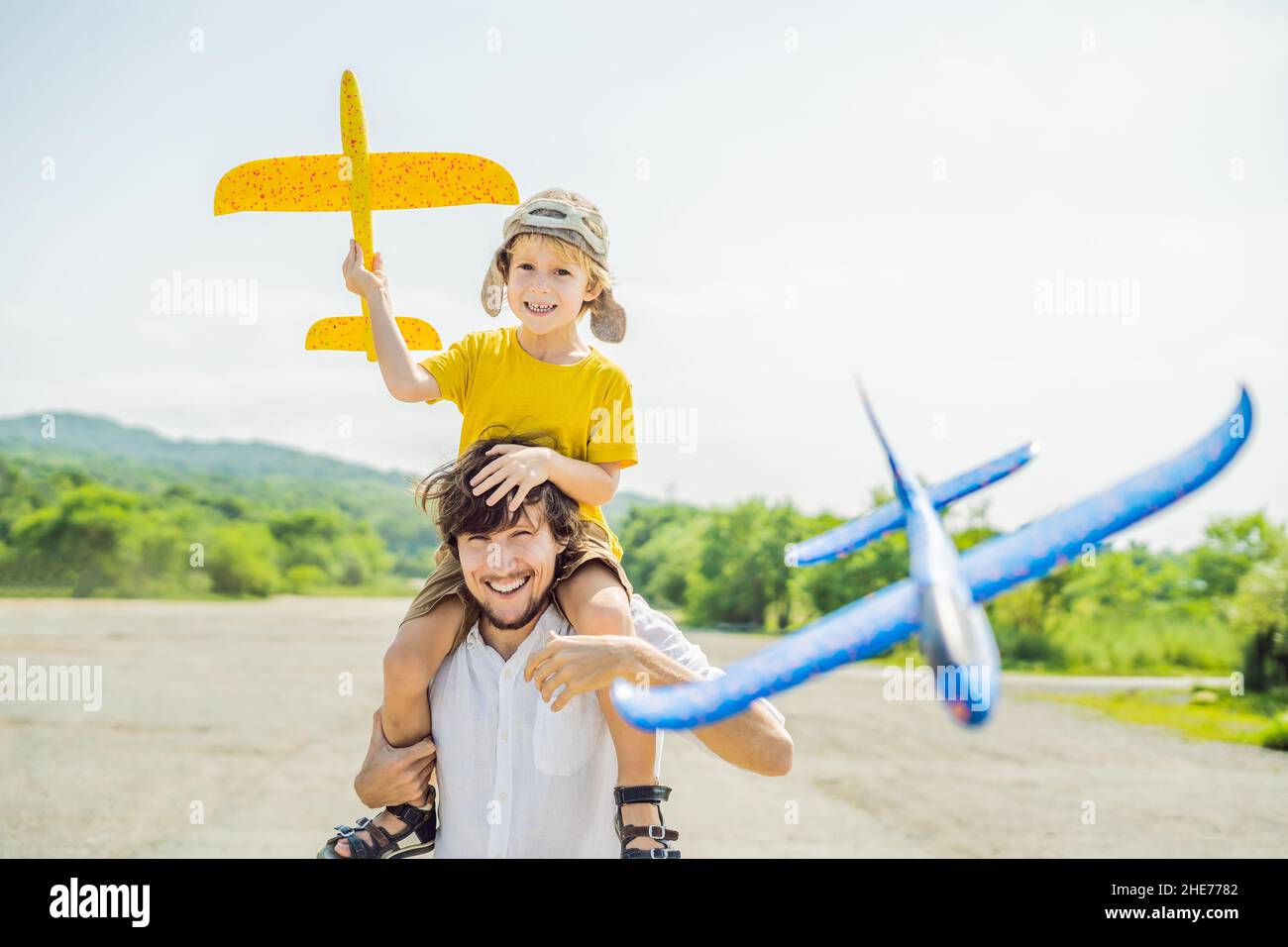 Happy father and son playing with toy airplane against old runway ...