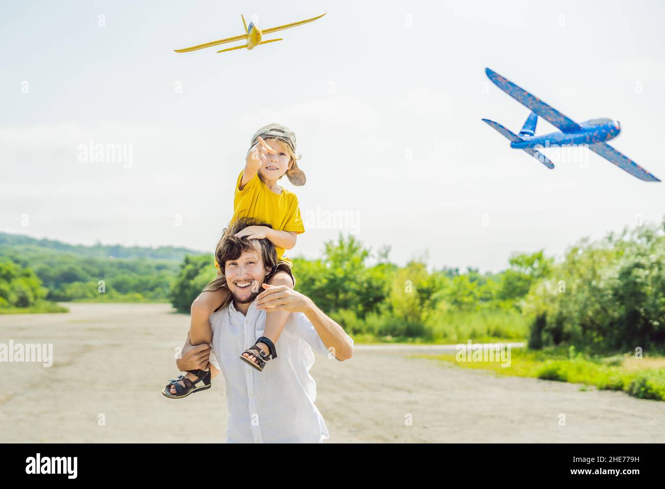 Happy father and son playing with toy airplane against old runway ...