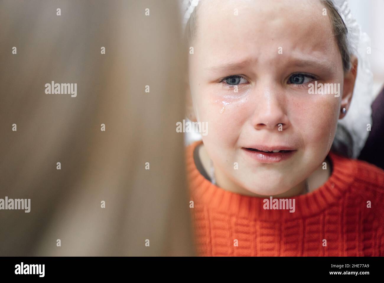 Portrait of little tearful girl in medical disposable cap crying in ...