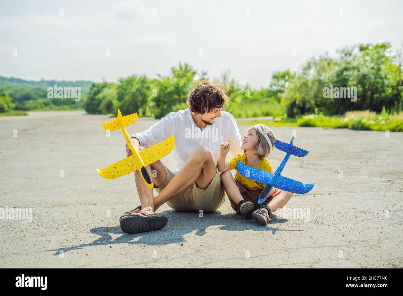 Happy father and son playing with toy airplane against old runway ...