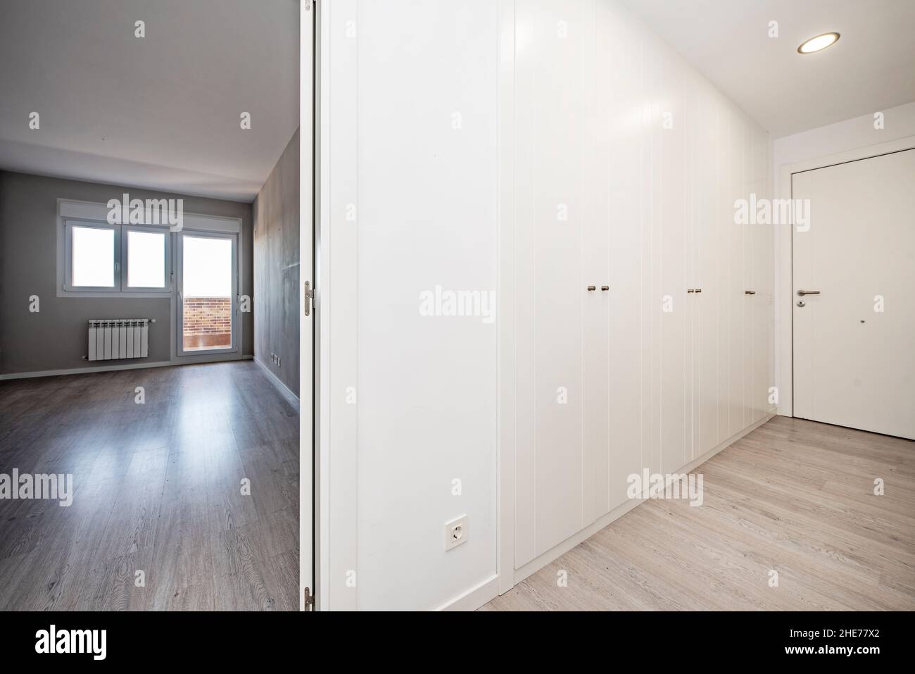 Corridor with a wall full of white cabinets and entrance to a living ...