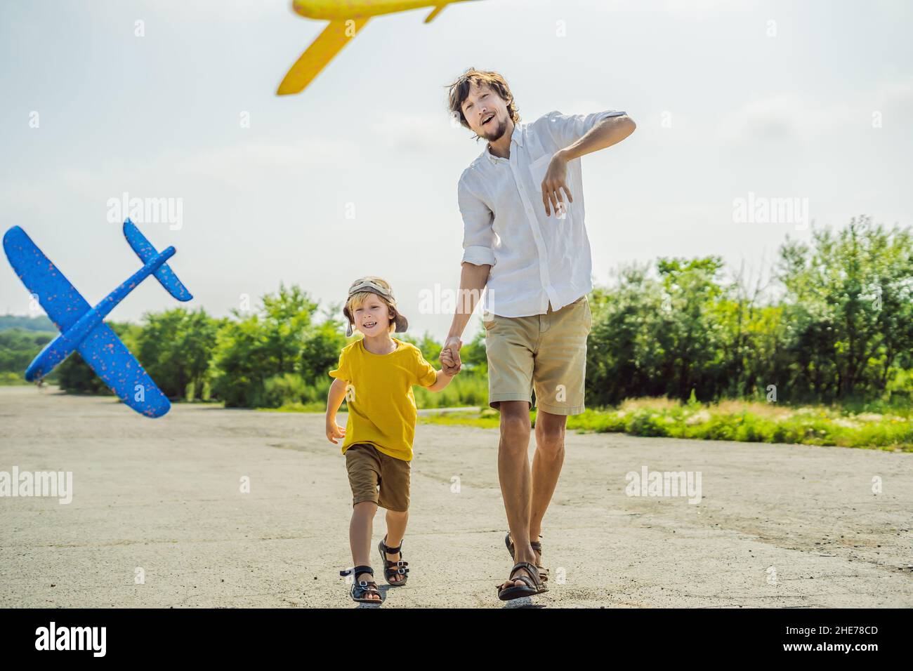 Happy father and son playing with toy airplane against old runway ...