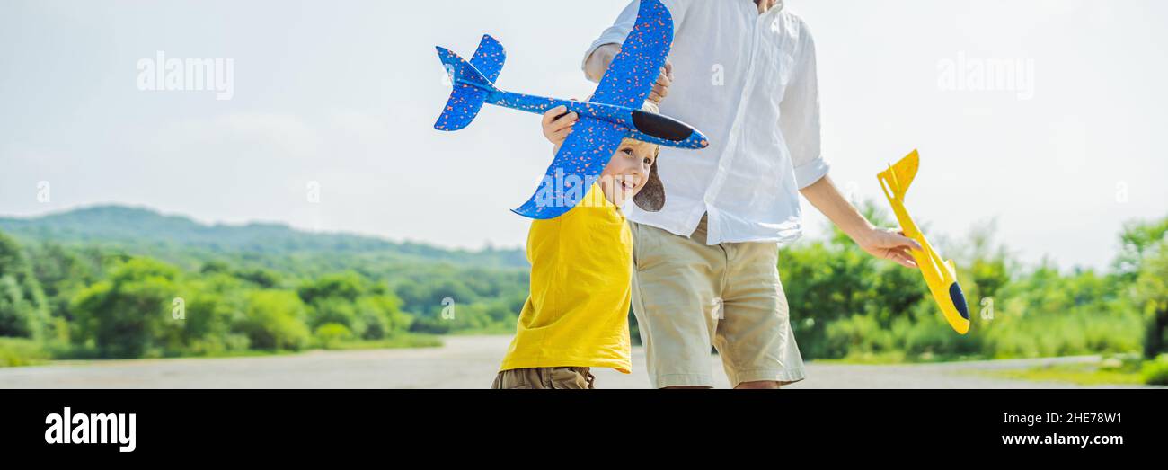 Happy father and son playing with toy airplane against old runway ...
