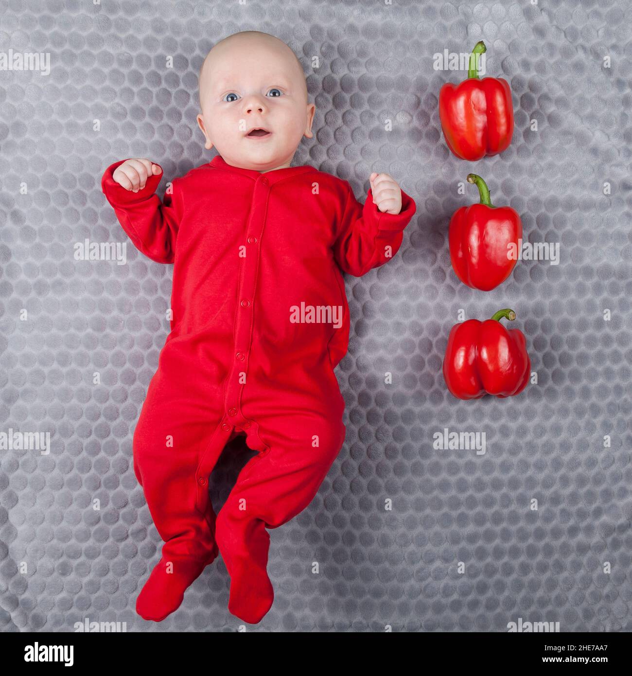 Smiling happy newborn infant three month baby in the red clothes with ...