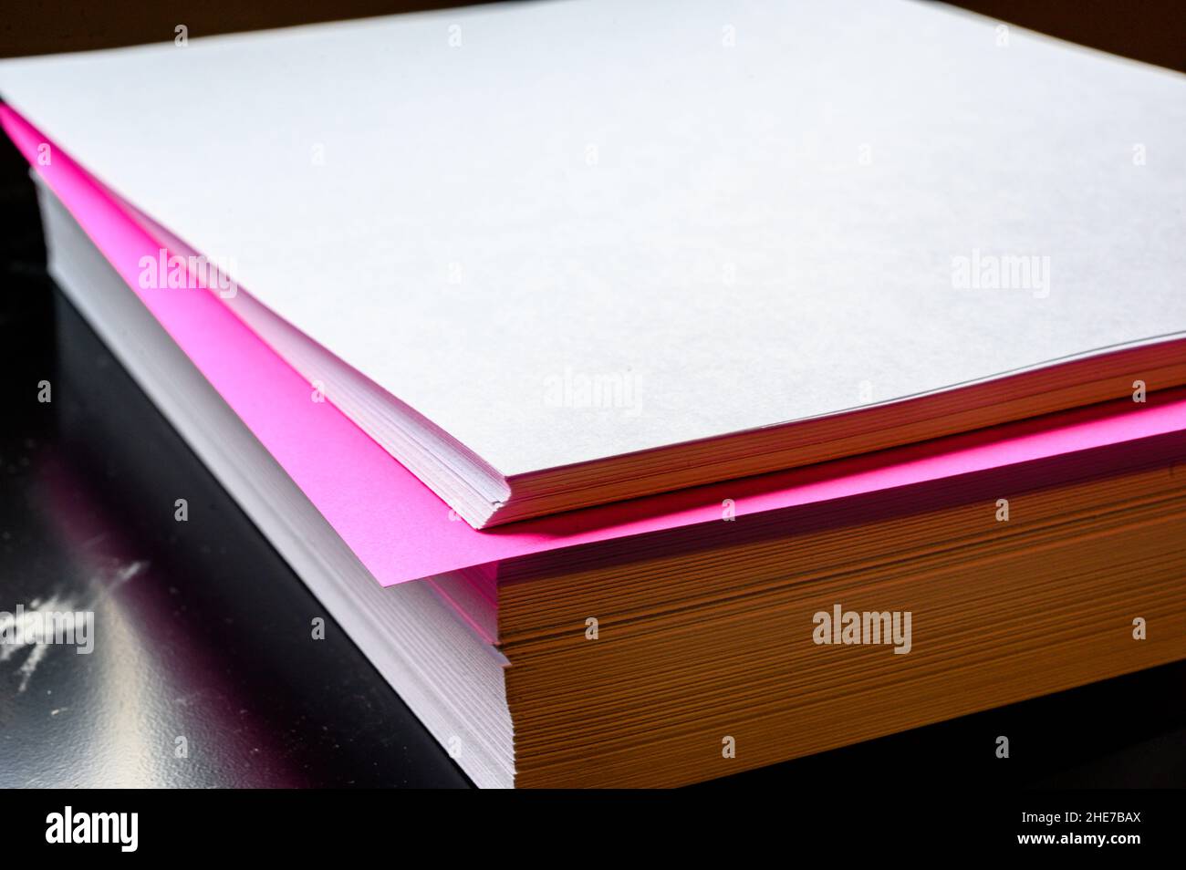 Selective focus on a single colored sheet in a stack of plain white ...