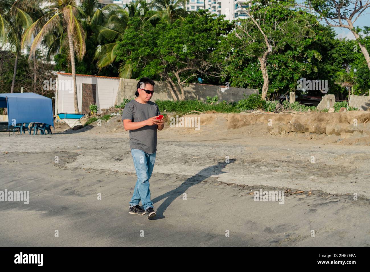Young Indigenous Colombian man walking whilst checking mobile phone ...