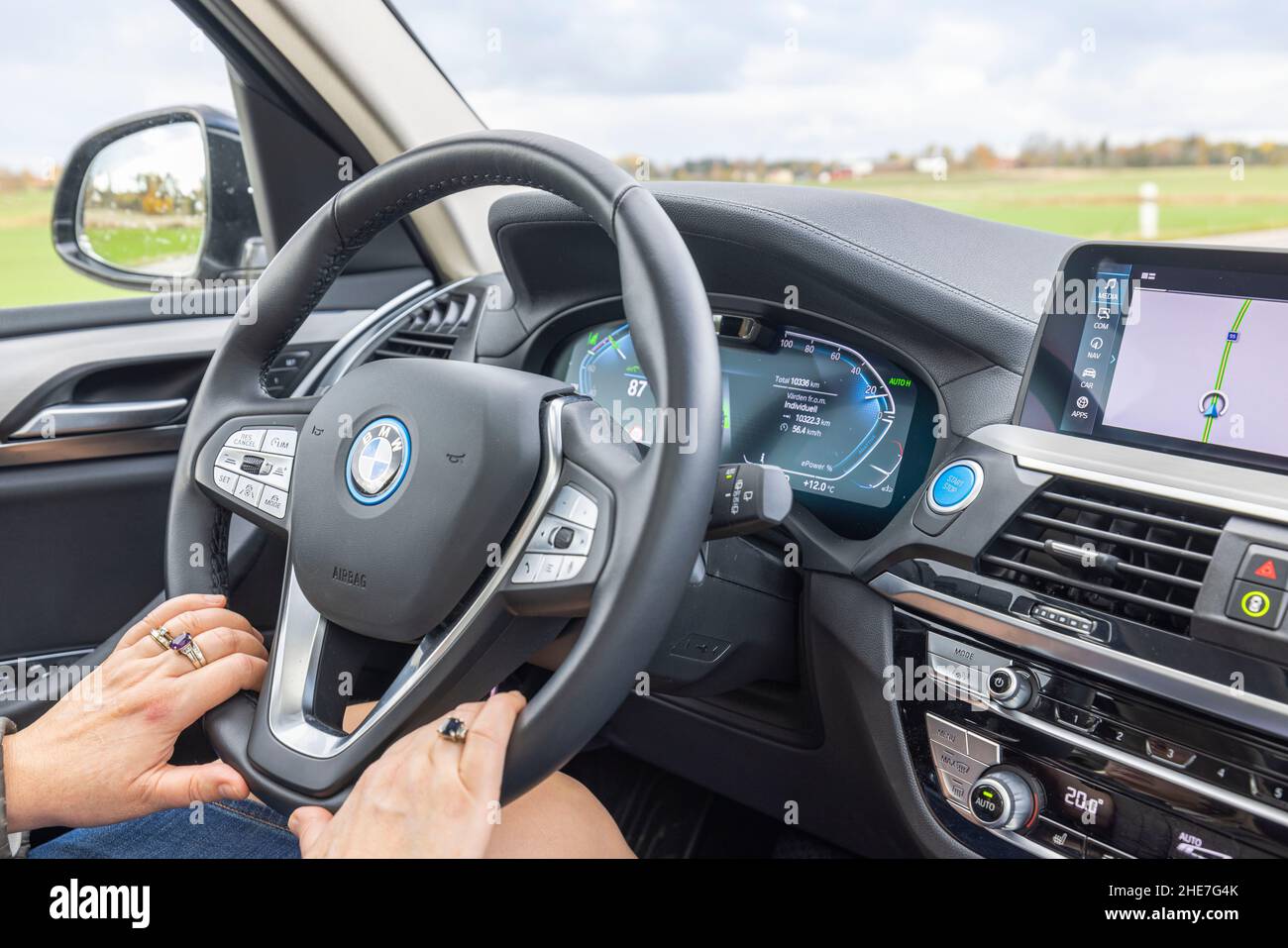 Beautiful interior view of BMW iX3 on road. Female driver in vehicle ...