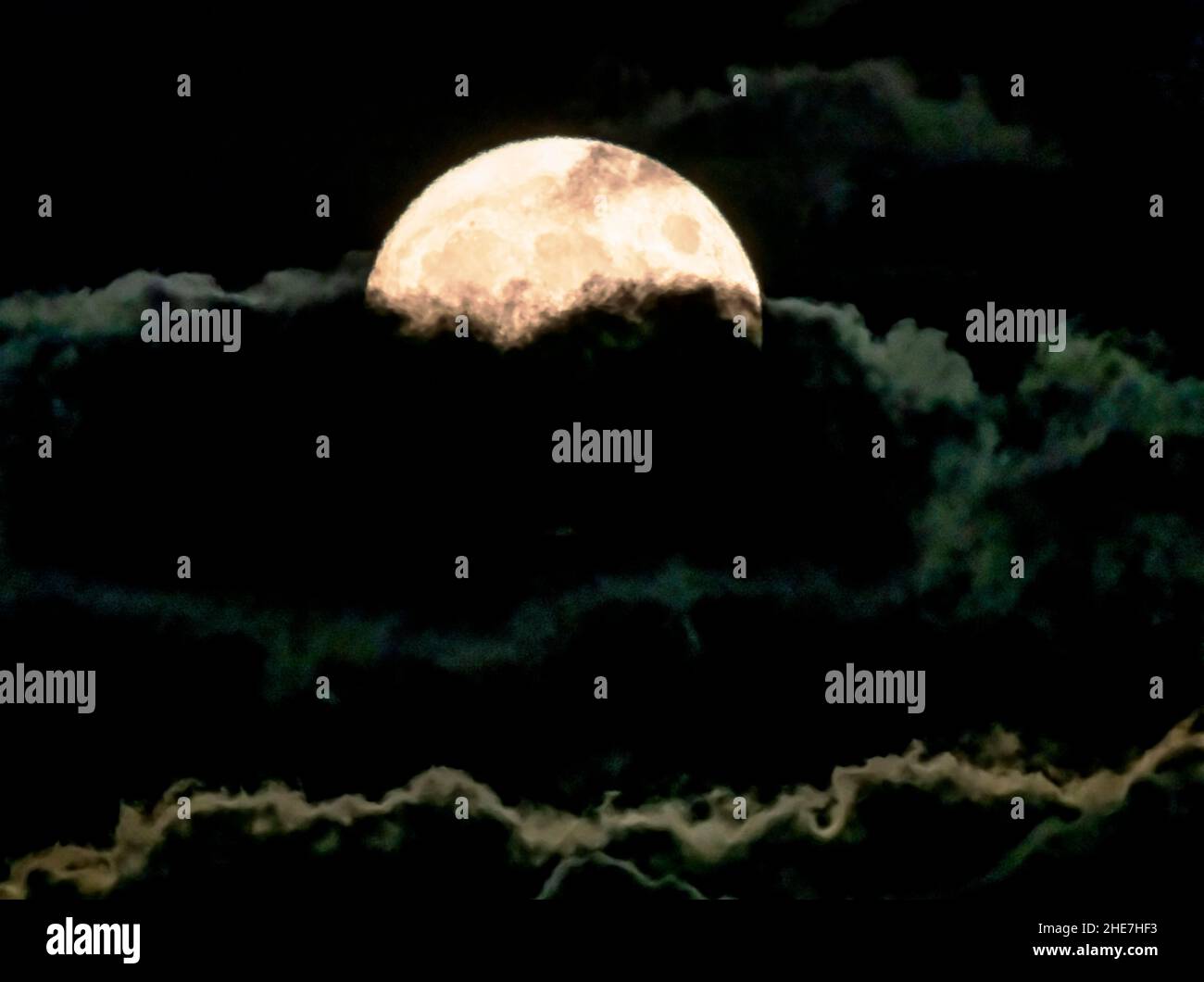 Clouds partially obscure Full Harvest Moon rising over Rocky Mountains ...