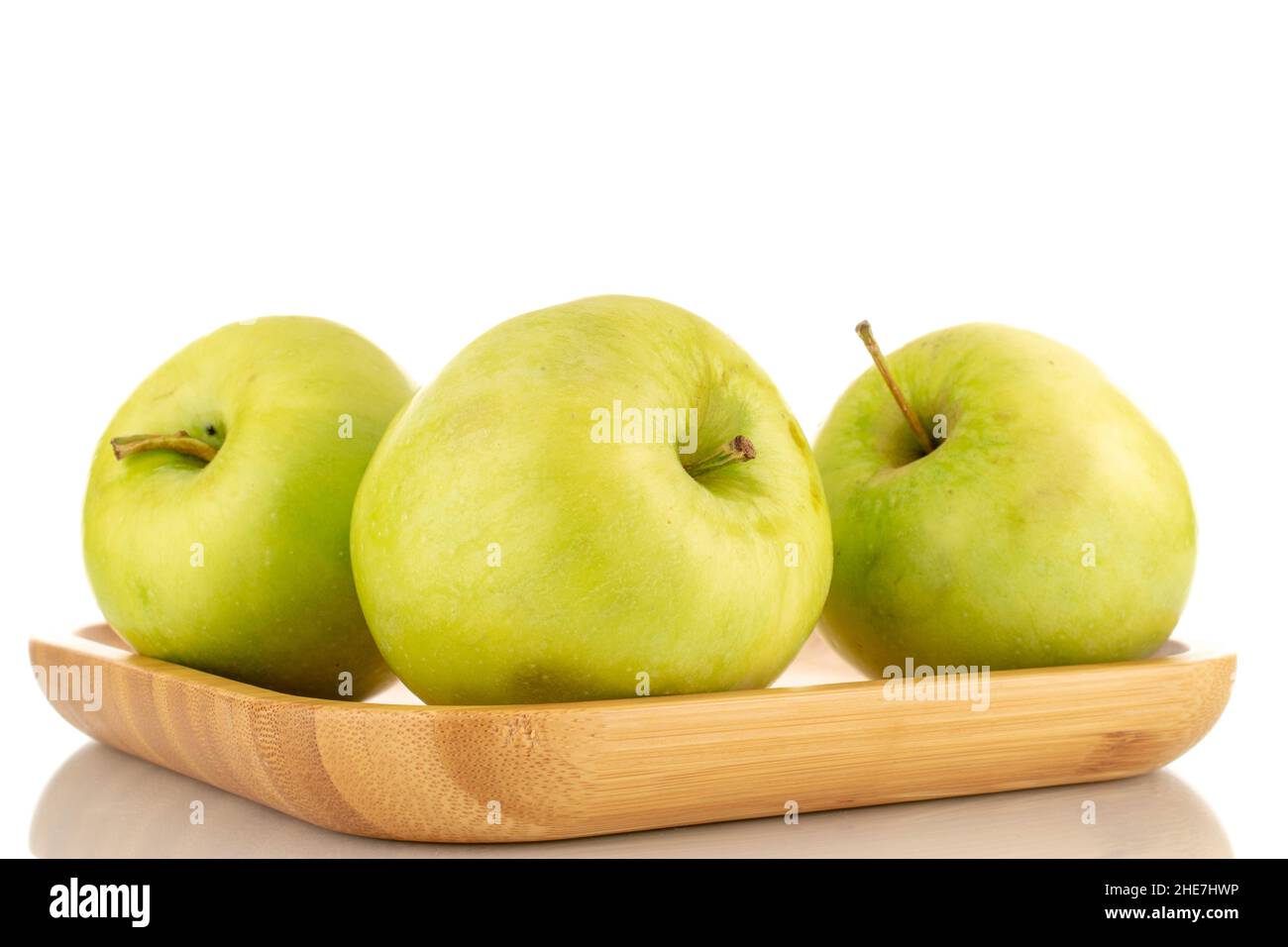 Three sweet green apples on a bamboo plate, close-up, isolated on white ...