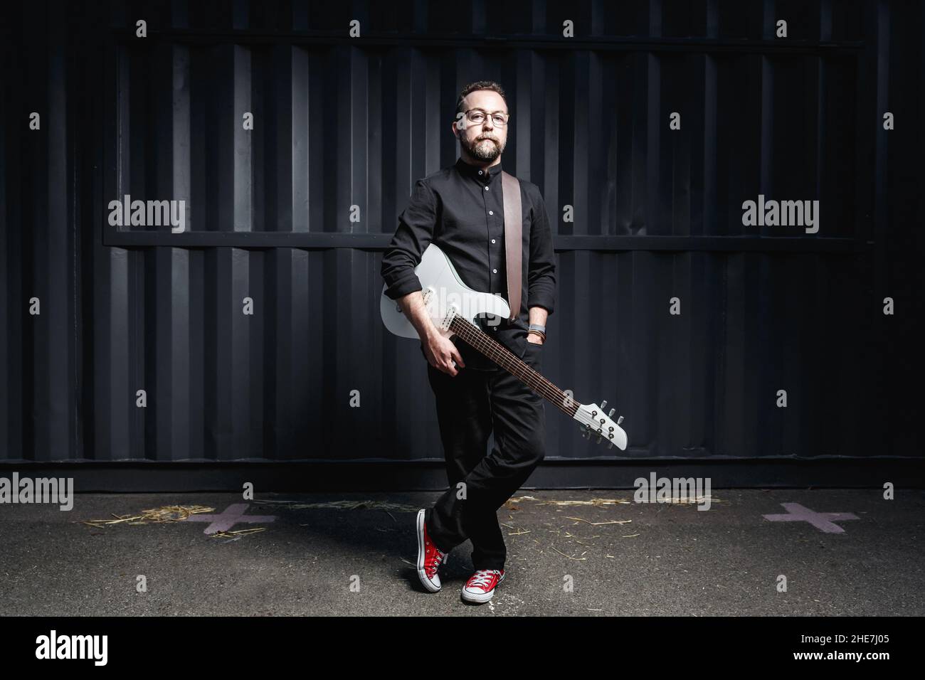 Portrait of a male guitar player with electric guitar wearing black ...