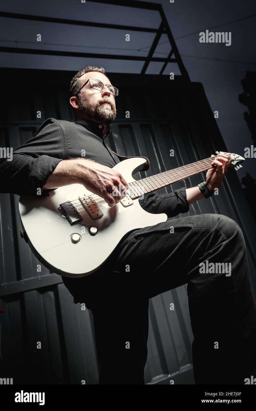 Portrait of a male guitar player with electric guitar wearing black ...