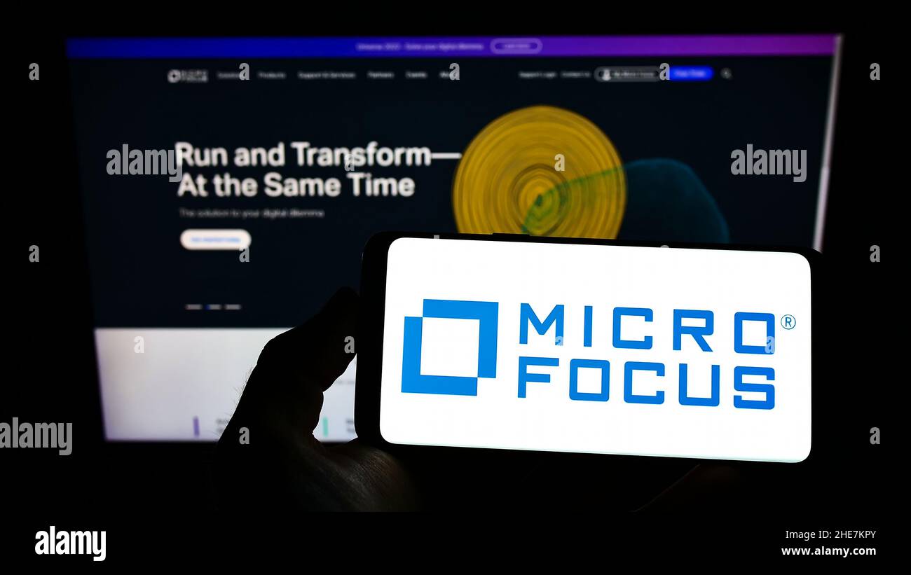 Person holding smartphone with logo of software company Micro Focus ...