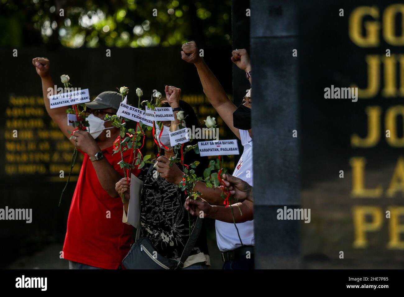 Human rights activists carry signs and offer flowers to remember fallen ...