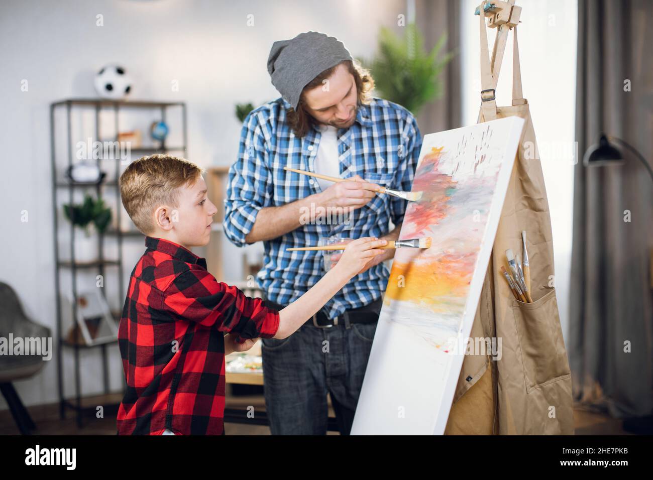 Handsome man and little boy in checkered shirts drawing abstract ...