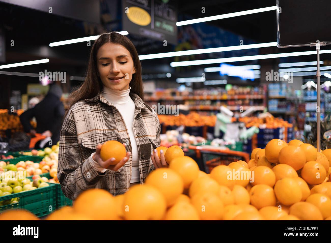 Woman buying oranges at grocery shop. Cheerful female shopper in the ...