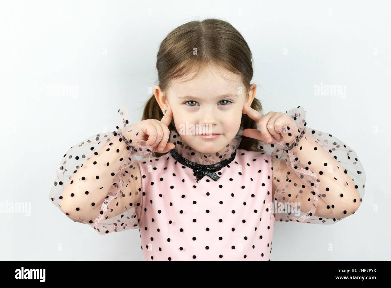Smiling little girl with two ponytails in a dress with polka dots on a ...