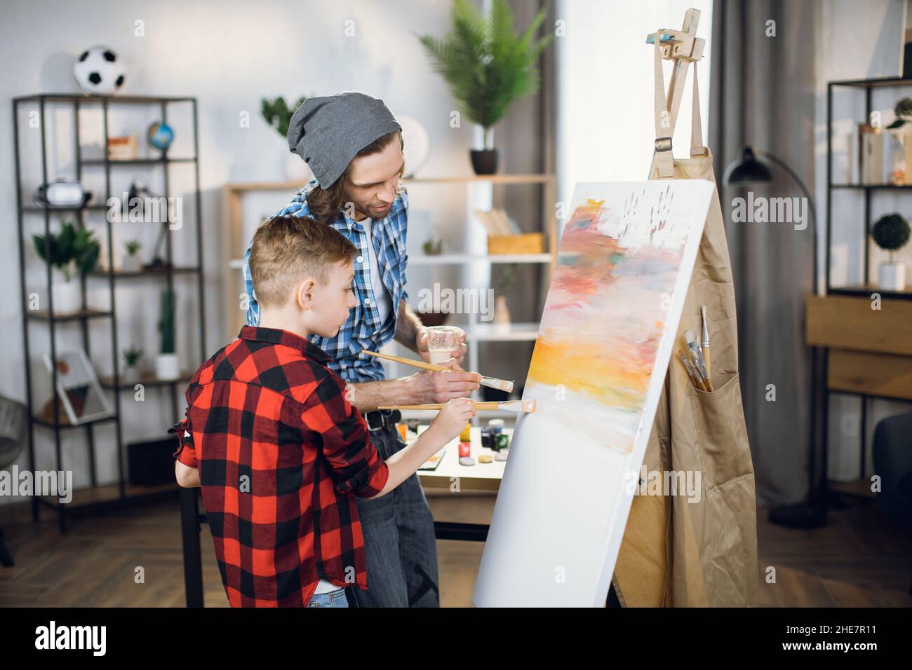 Caucasian father drawing with son with colorful paints and brush at ...