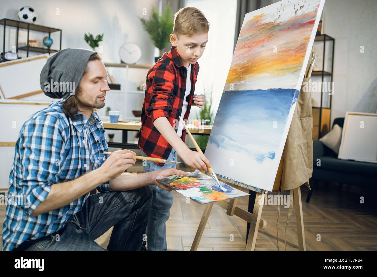 Cute caucasian boy in casual wear using palette and brush for painting ...