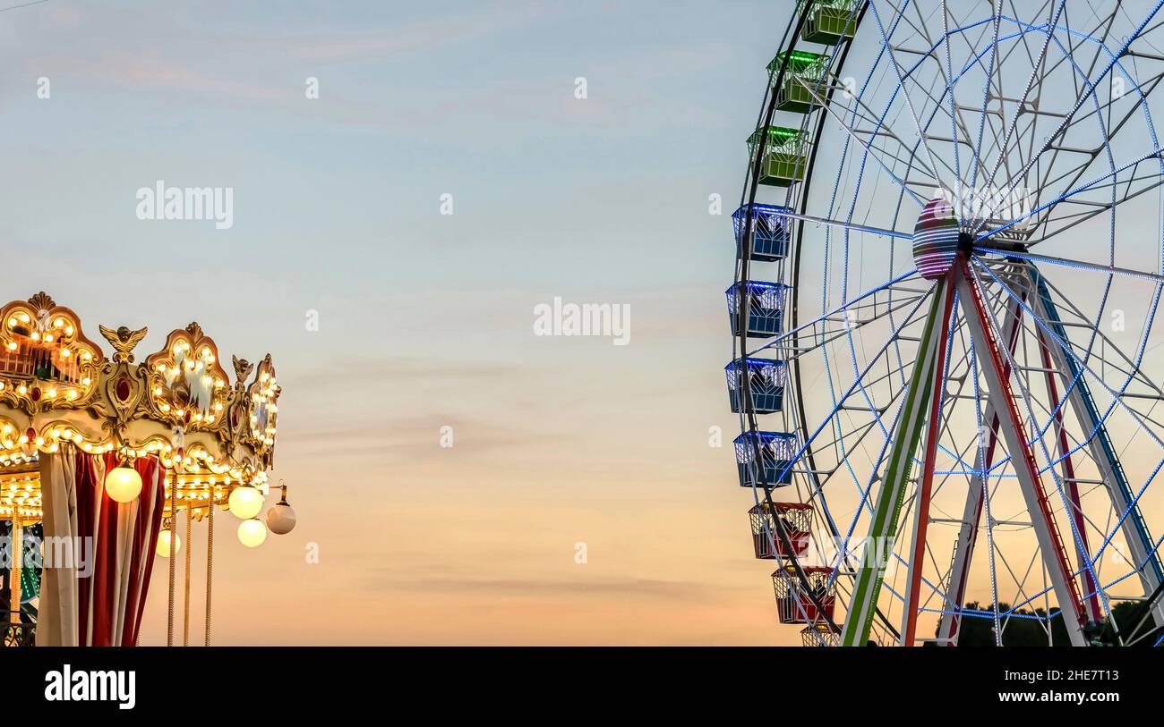 Ferris wheel in a fairground park next to a carousel Stock Photo - Alamy