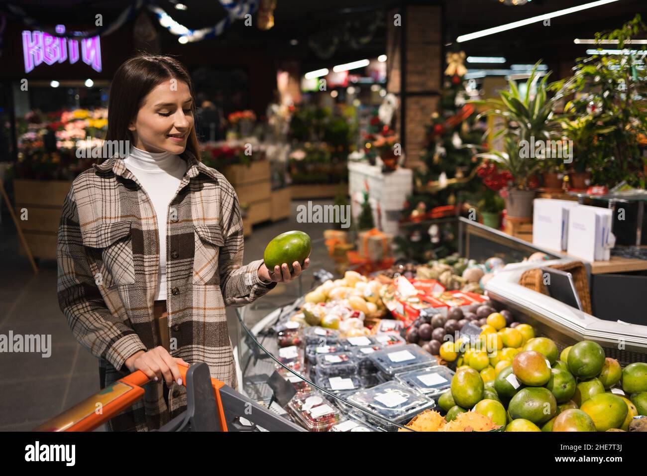 Happy Young Woman Choosing Ripe Mango in Grocery Store Stock Photo - Alamy