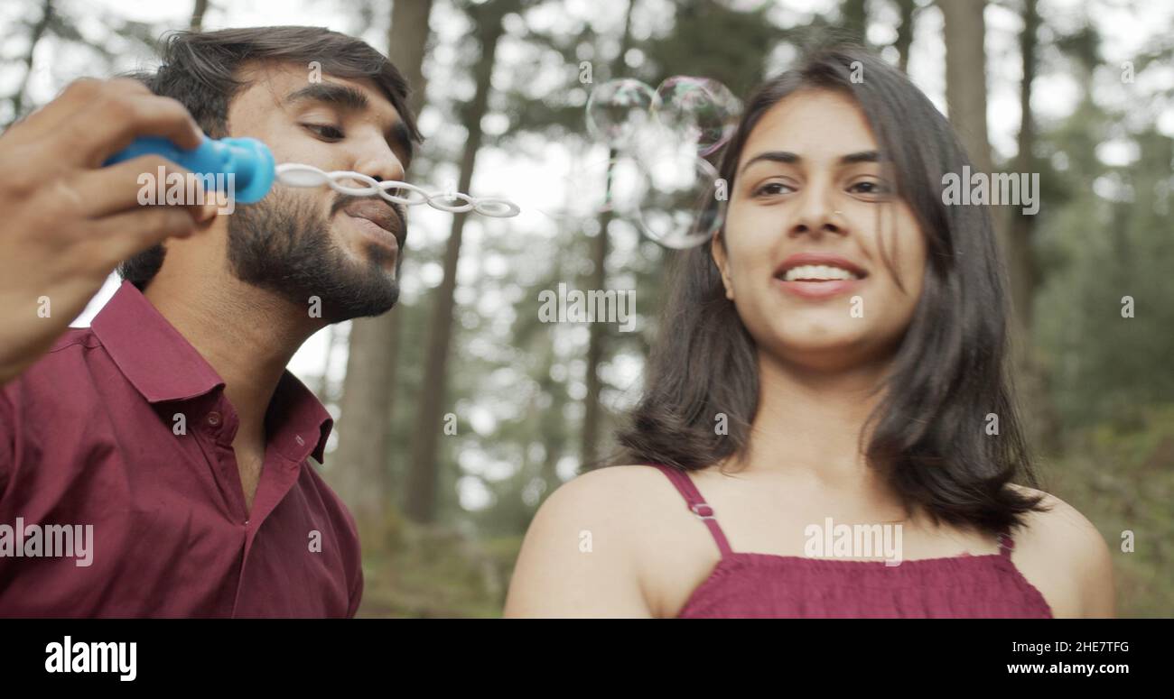 Young Indian couple bowing bubbles while on a date at a park Stock ...