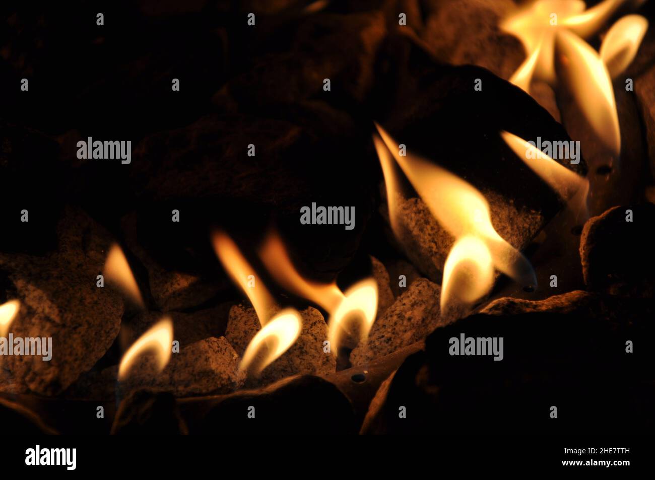 Small flames in the night on a black surface. Fire flames on black ...