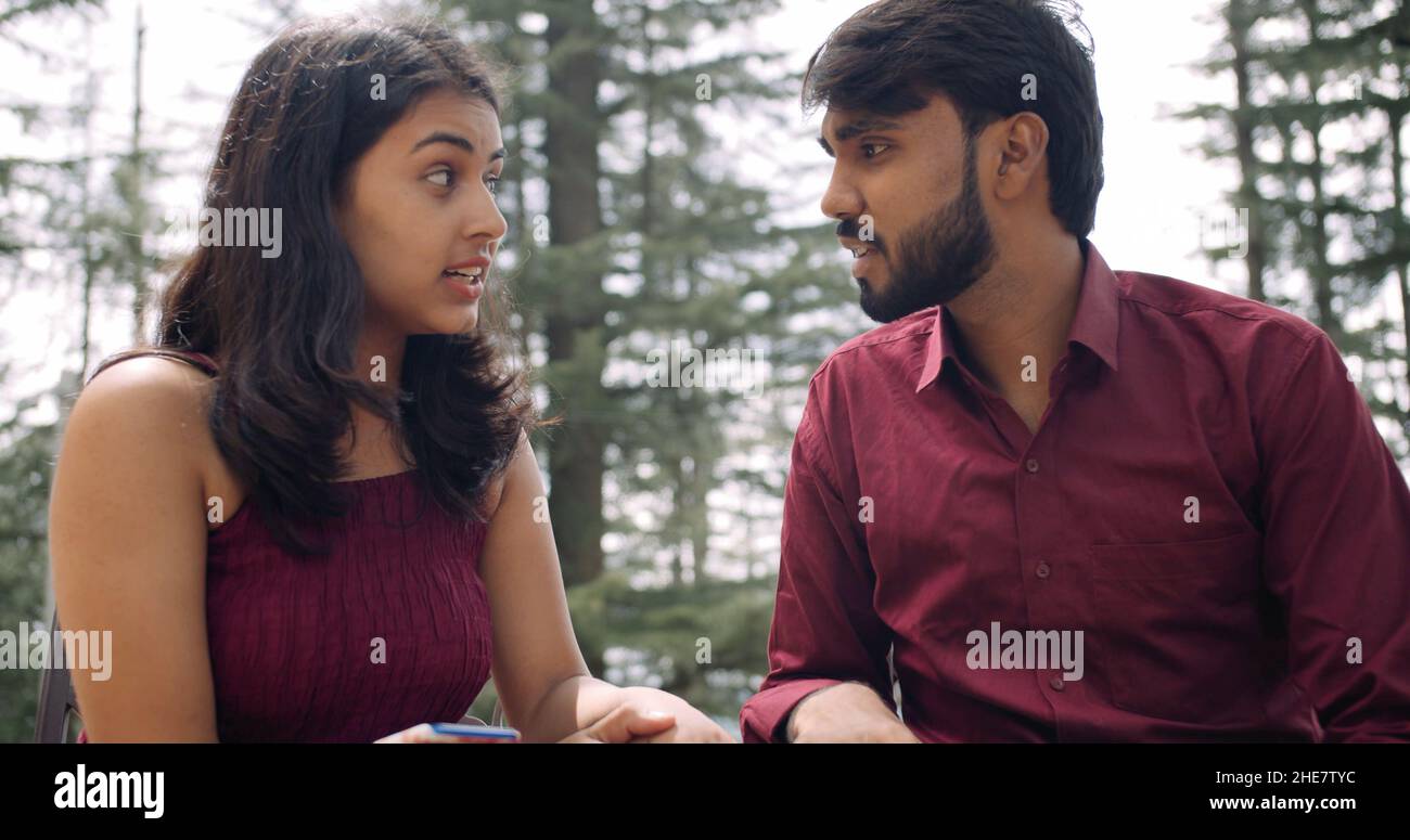 Young Indian couple having a conversation while seated at a park Stock ...