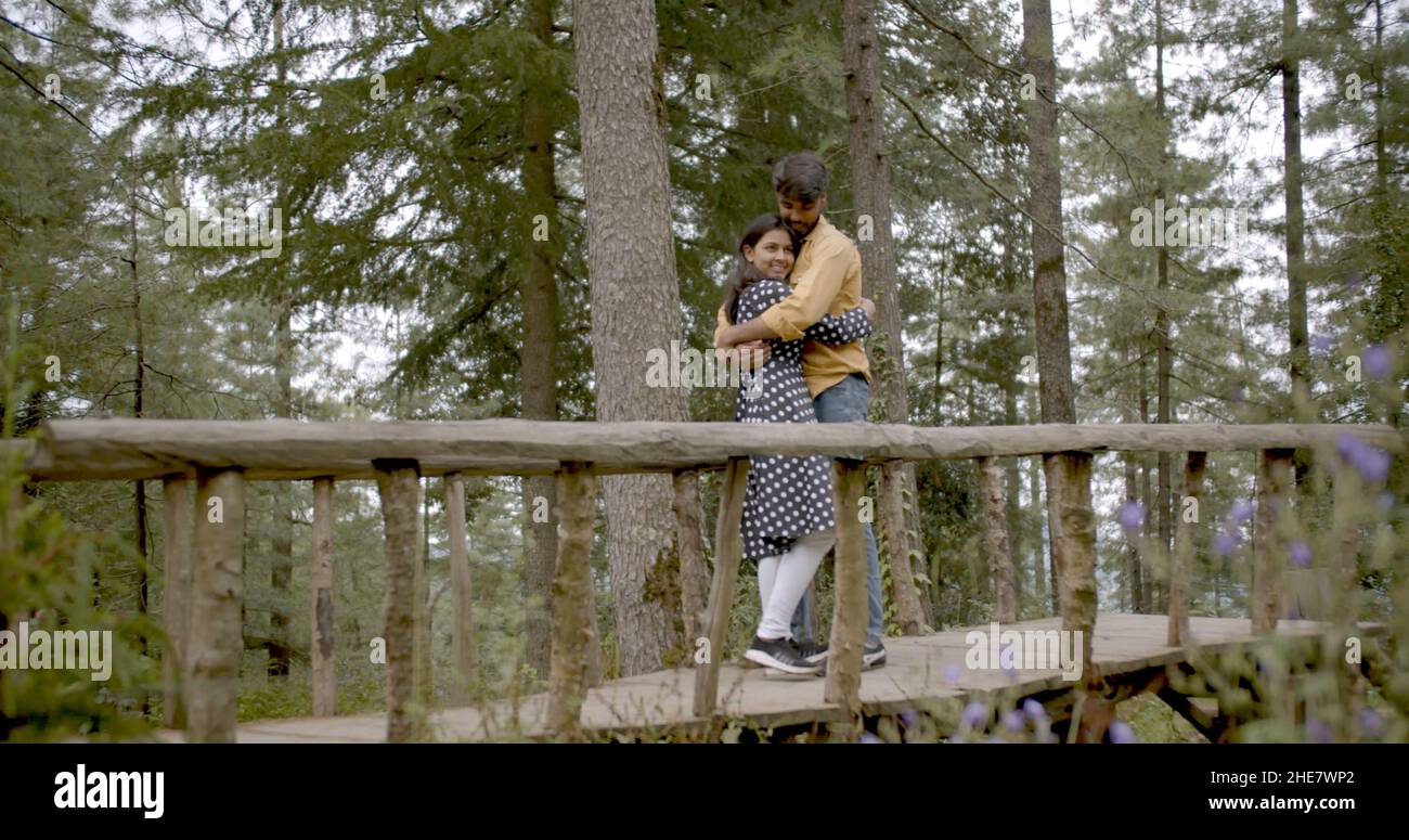 Young Indian couple giving each other a hug on a wooden bridge at a ...