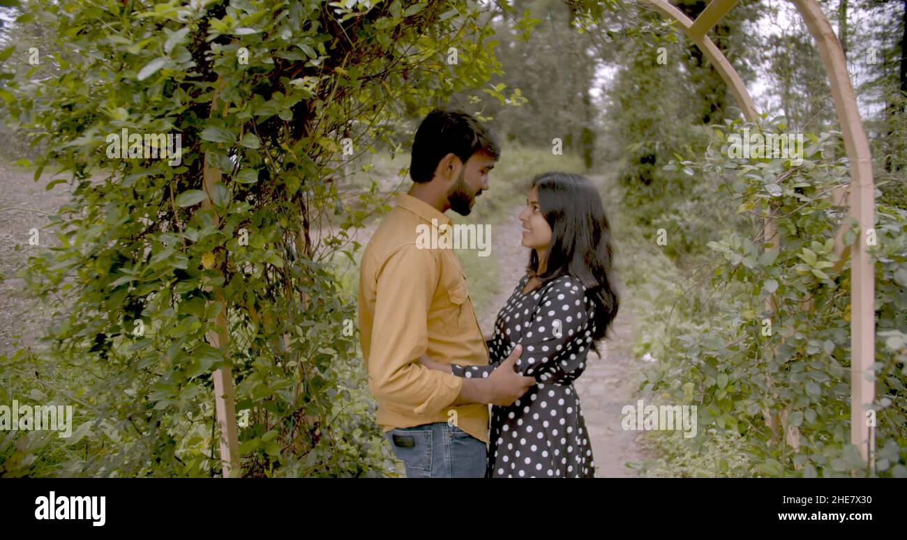 Young Indian couple being affectionate under a wooden arc during a date ...