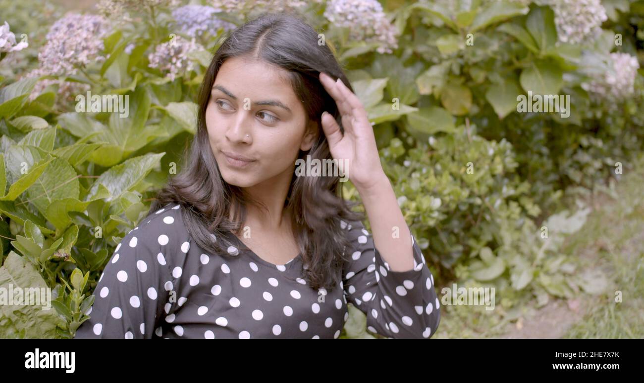 Beautiful Indian woman posed against blooming hydrangea plants at a ...