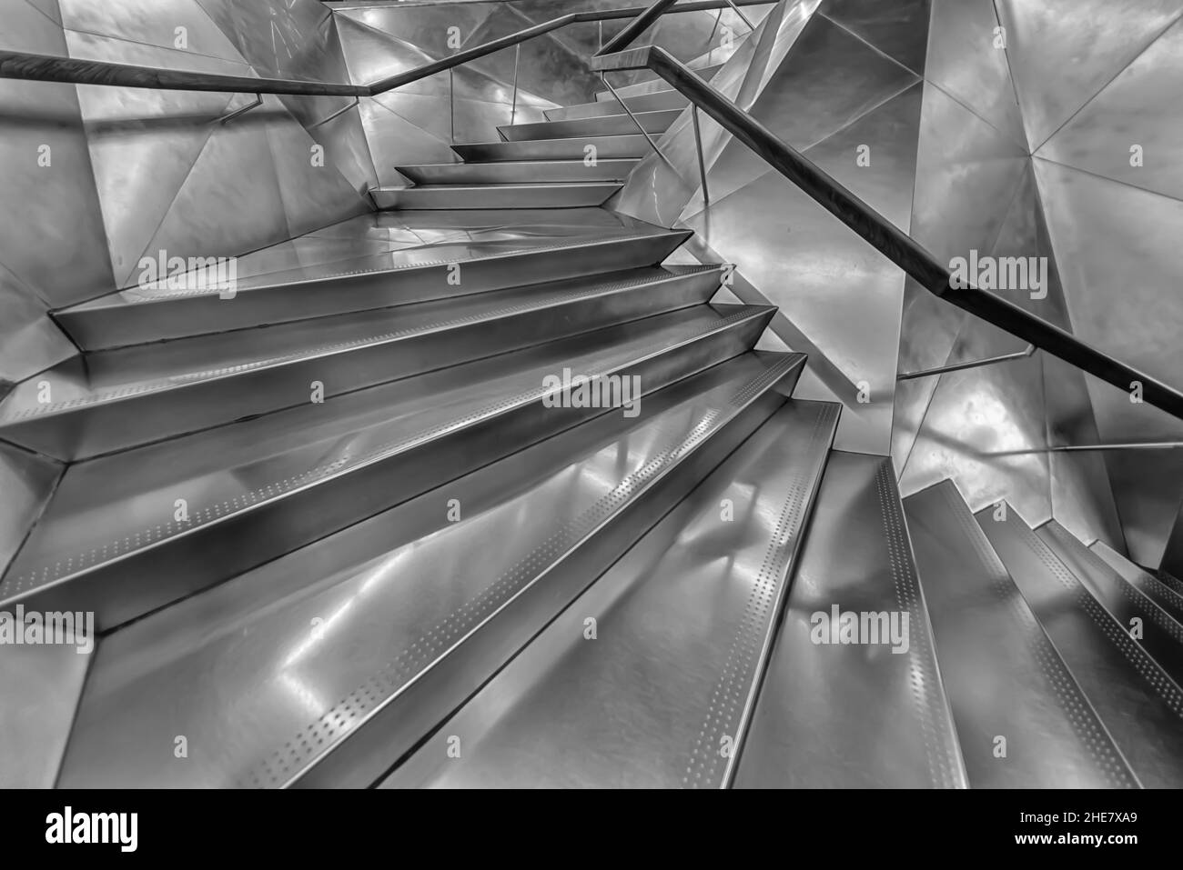 A silver metal staircase curving upwards with psychedelic lights giving ...