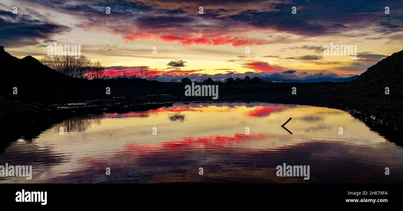 Panoramic view of a dark landscape and sunset sky reflection in the tranquil sea Stock Photo - Alamy