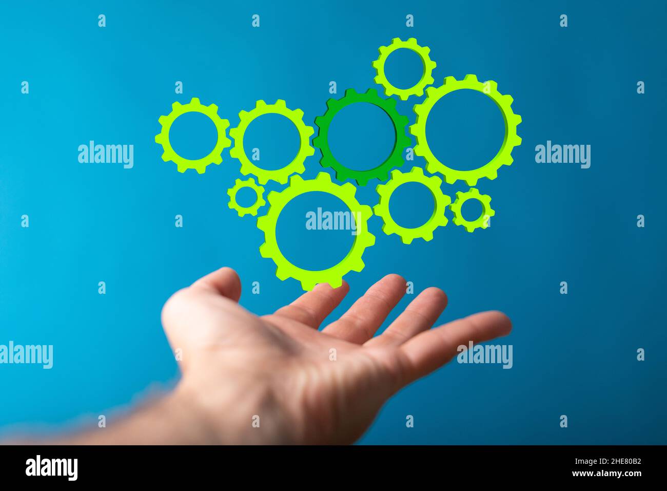 Hand holding Set of green gears and cogs on black background with a ...