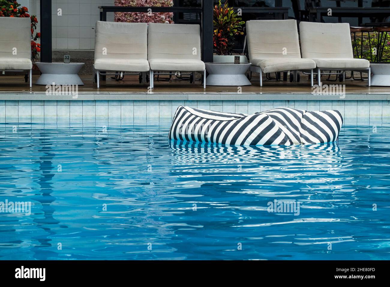 Striped pillows floating in a hotel pool with blue water and relaxing ...