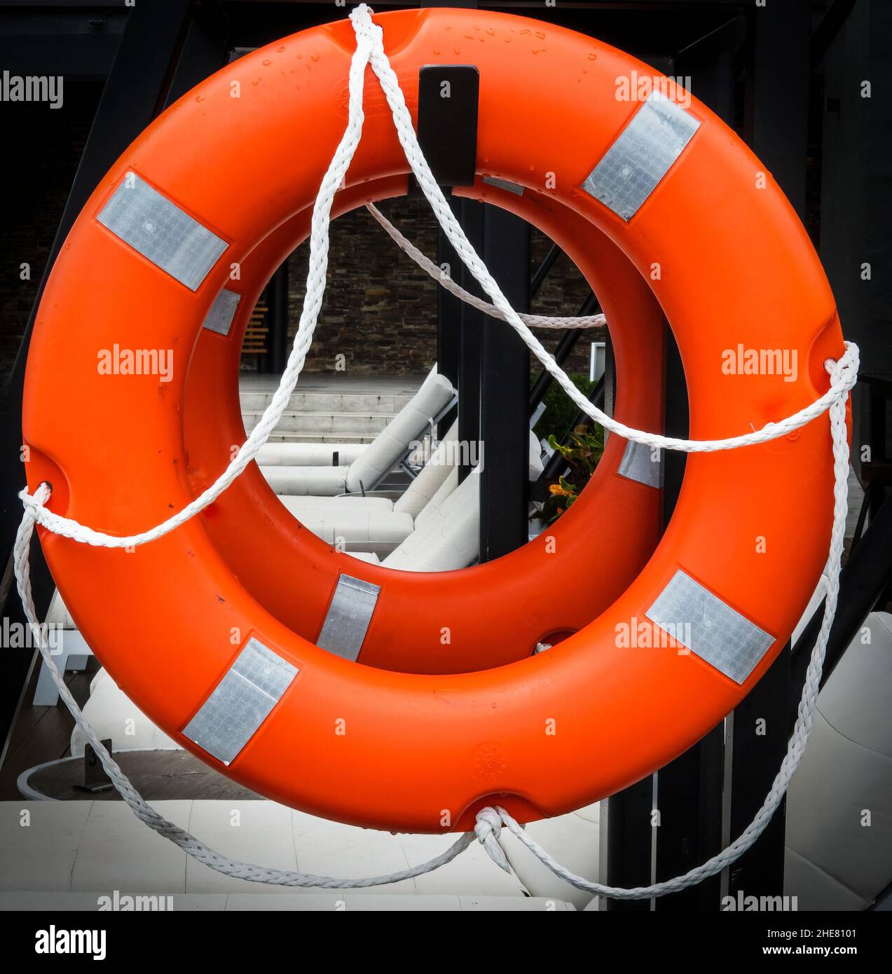 A lifesaving orange inflatable ring tube on a wall for tossing to ...