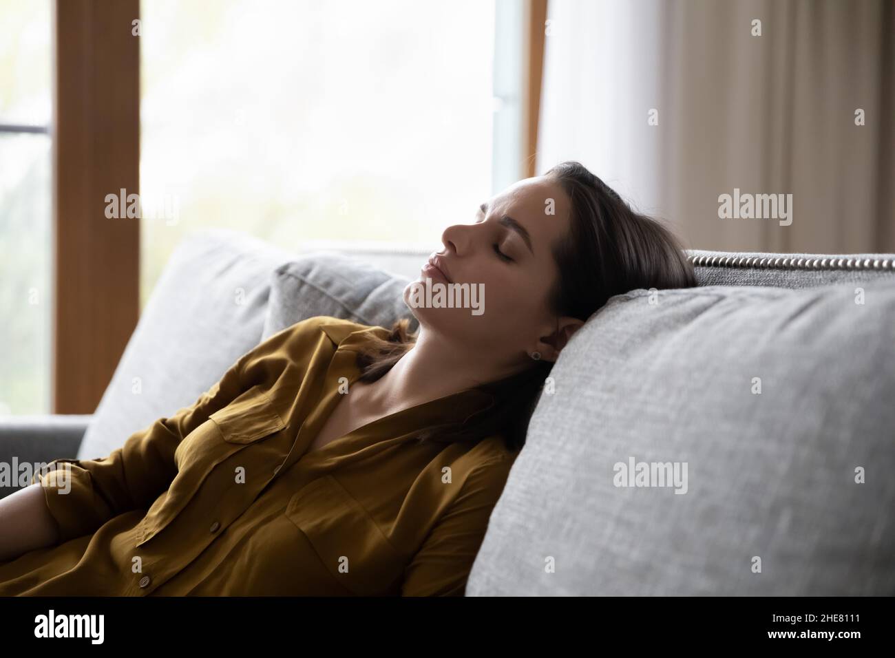 Tired millennial young woman sleeping in sitting position on couch ...