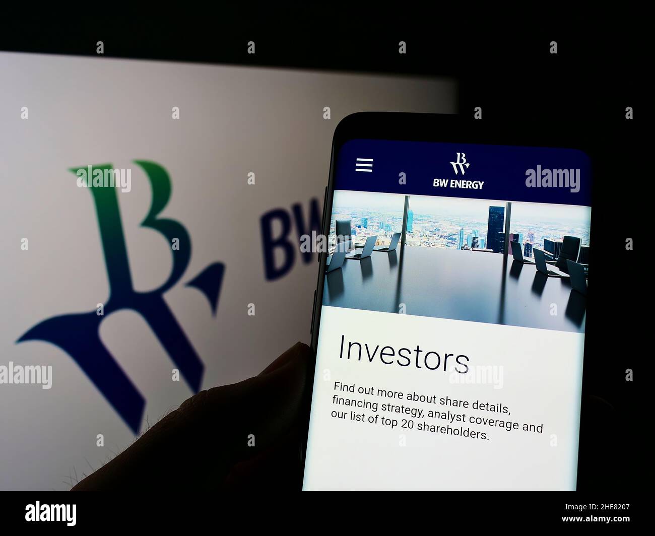 Person holding cellphone with webpage of Norwegian oil and gas company ...