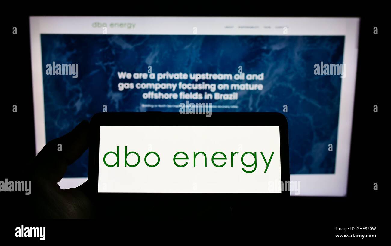 Person holding mobile phone with logo of Brazilian oil and gas company ...