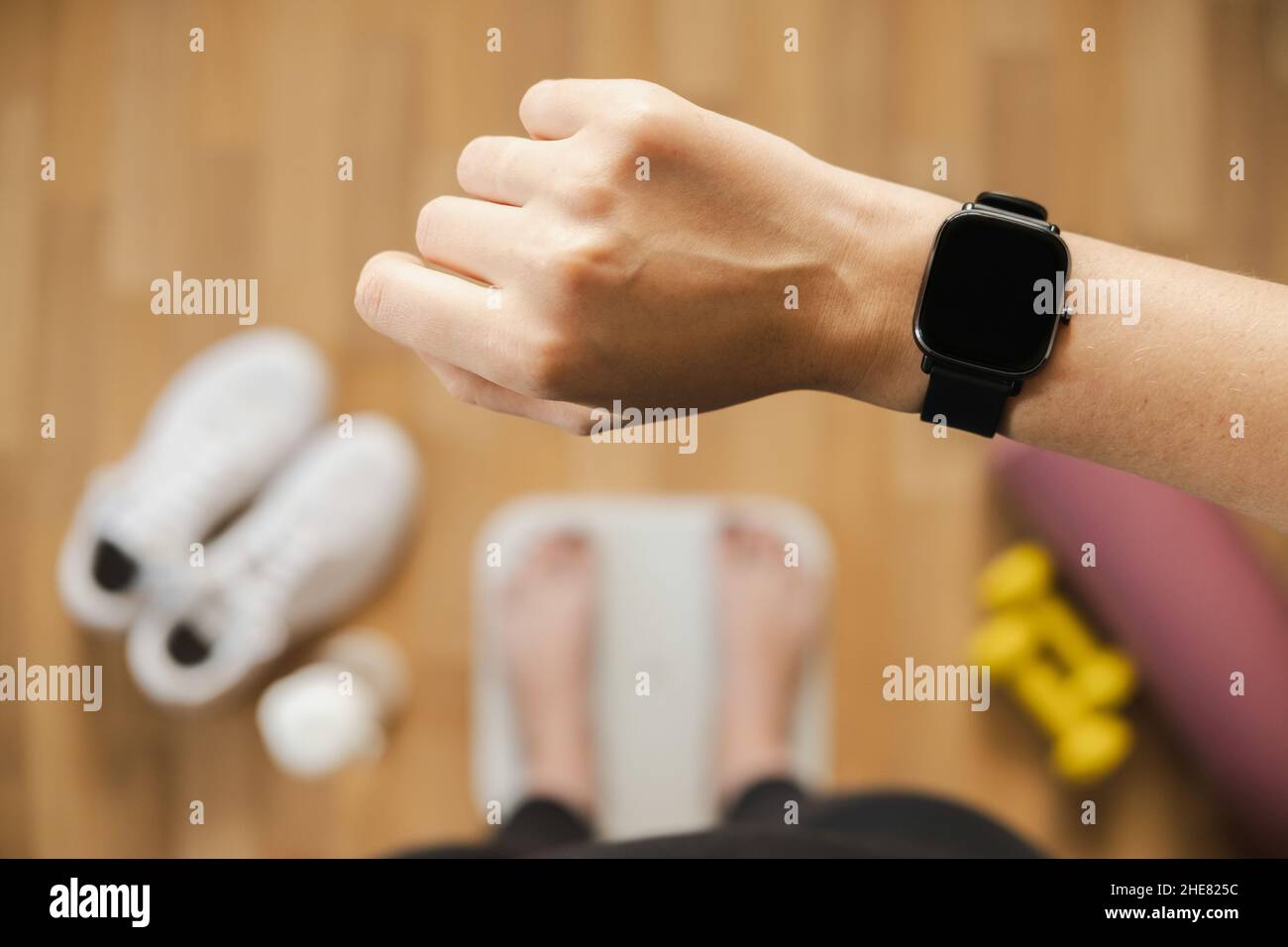 Looking at fitness tracker while standing on scales, first person view ...