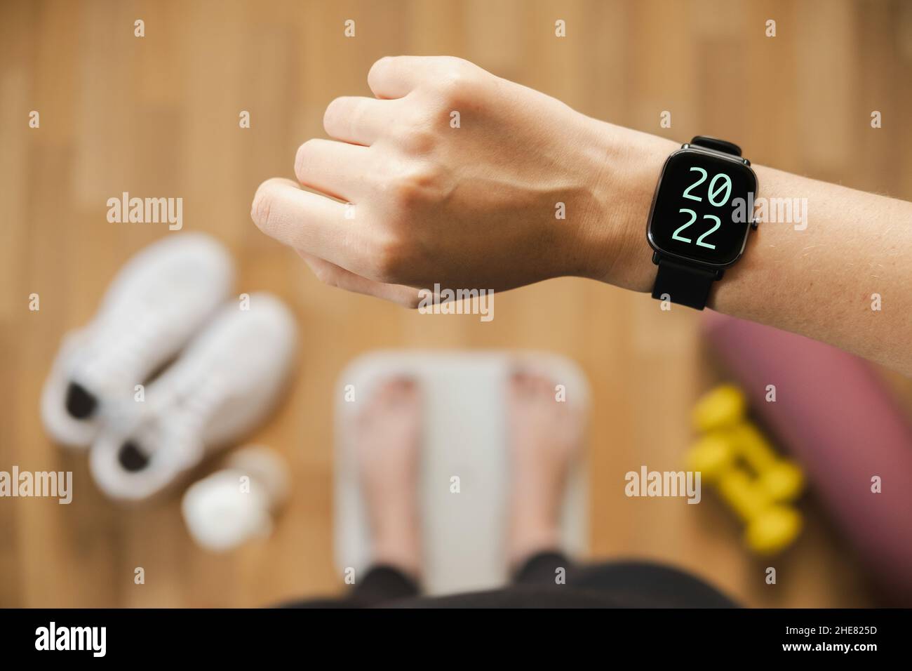 Looking at fitness tracker with 2022 number while standing on scales ...